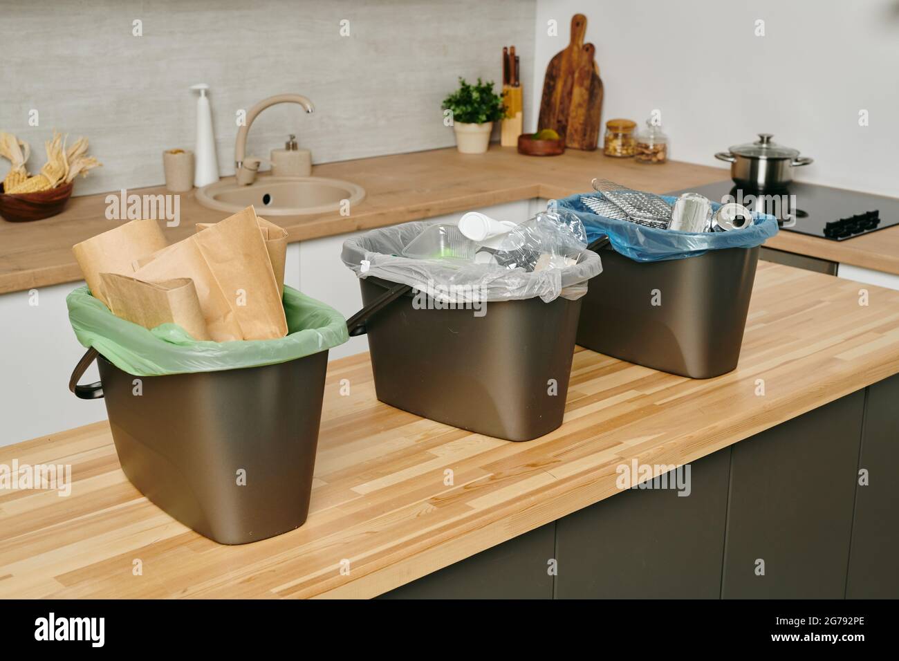 Three garbage bins with sorted waste on kitchen table Stock Photo - Alamy