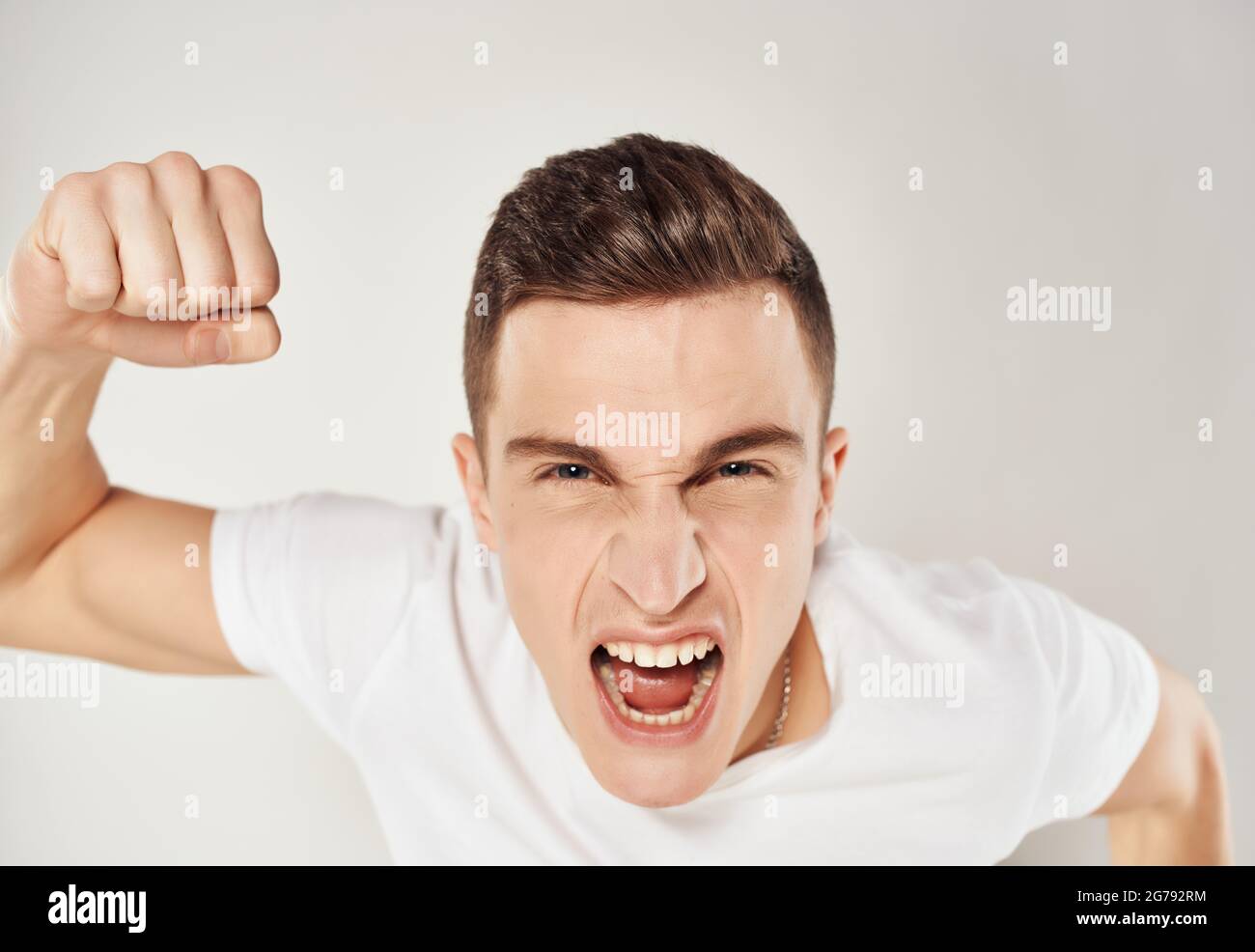 mad man in white t-shirt emotion light background Stock Photo - Alamy