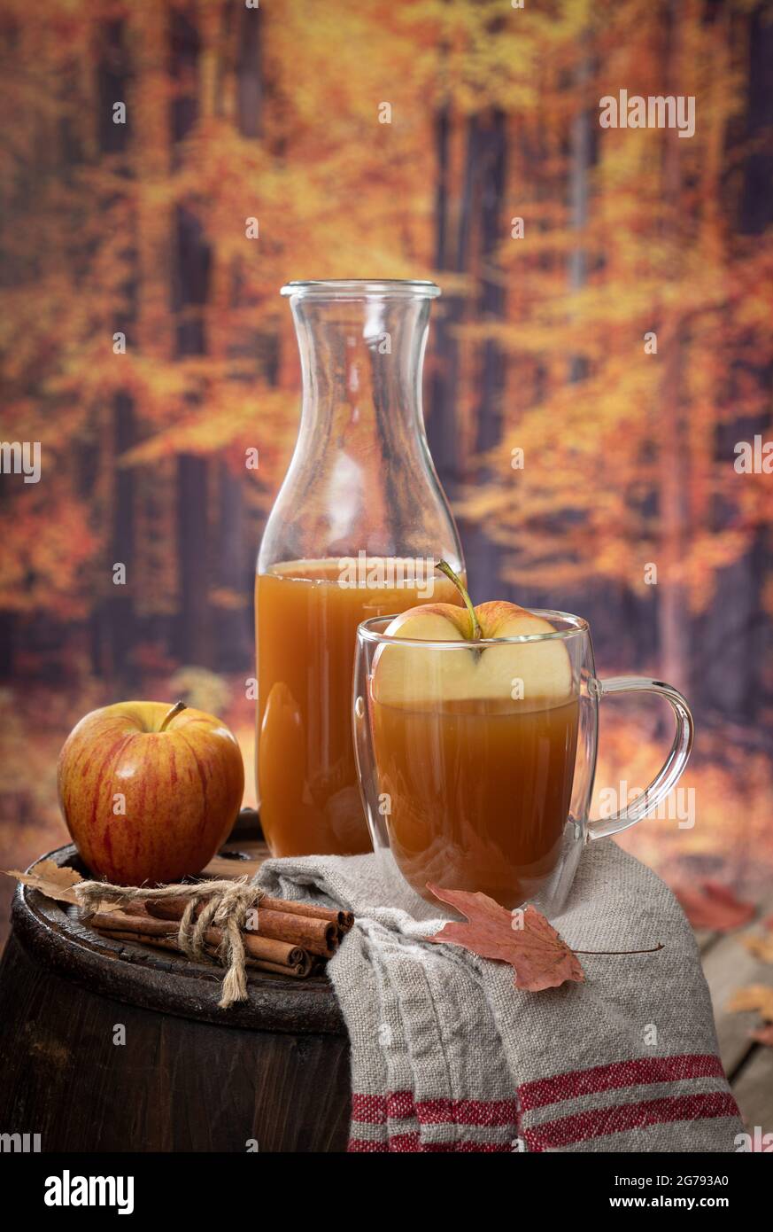 Apple cider in a glass cup and carafe on a wooden barrel with autumn ...