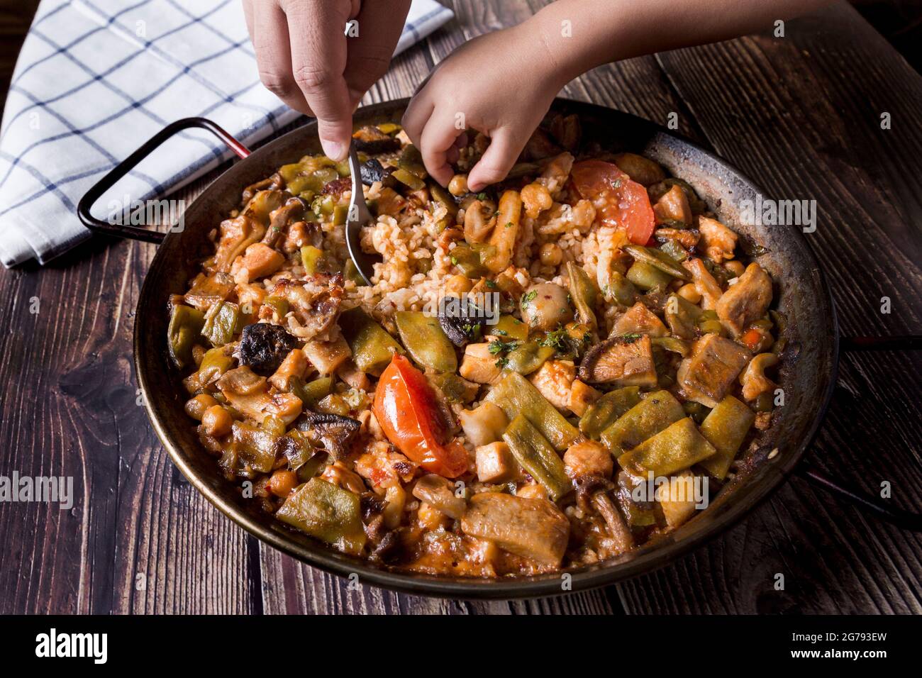 A man's hand and a child's hand tasting paella. Time to share with dad ...