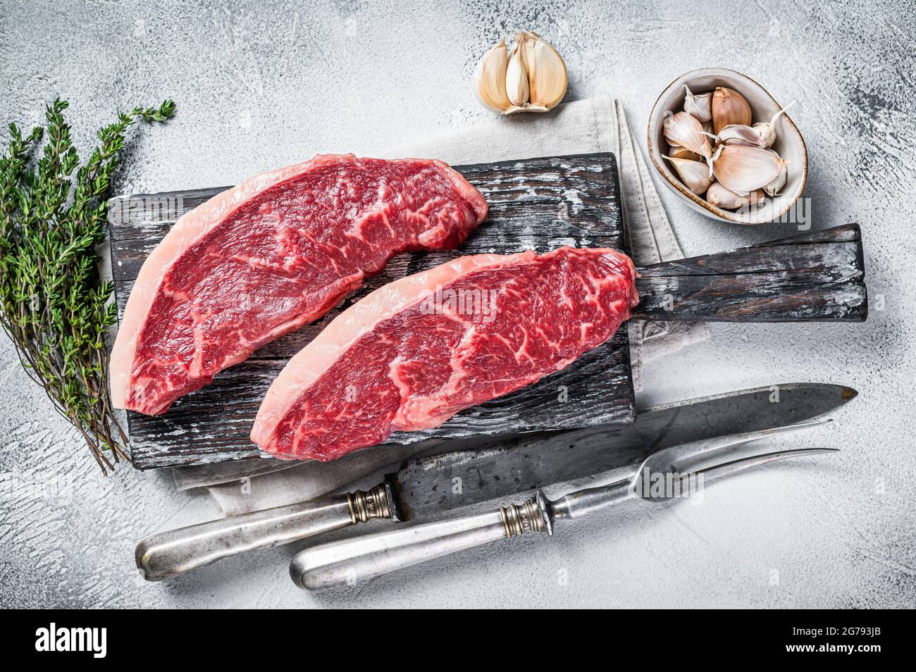 Raw rump beef meat steaks on wooden board with meat knife and fork ...