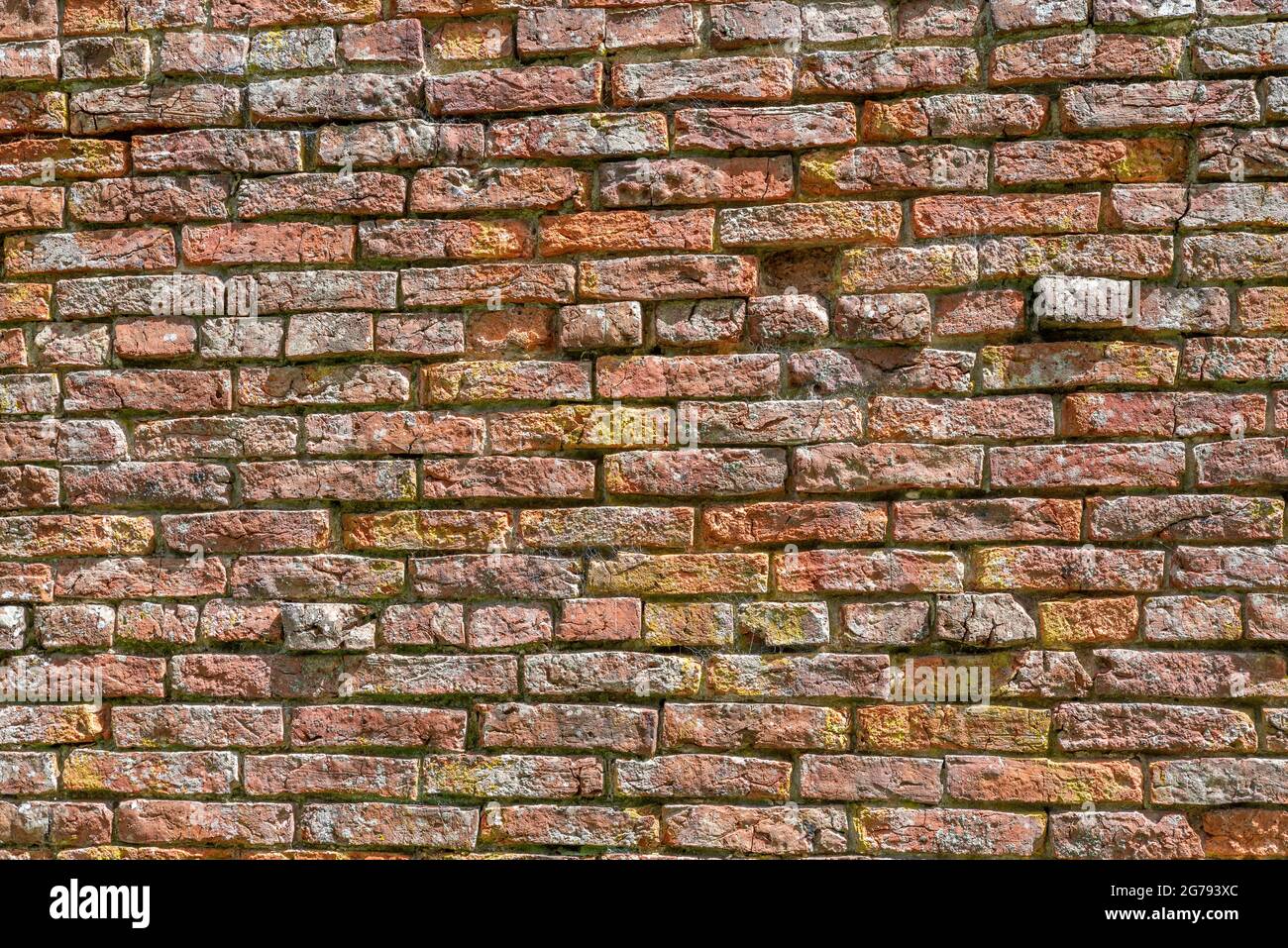 Rough red brick wall weathered and discoloured with old bricks on a ...