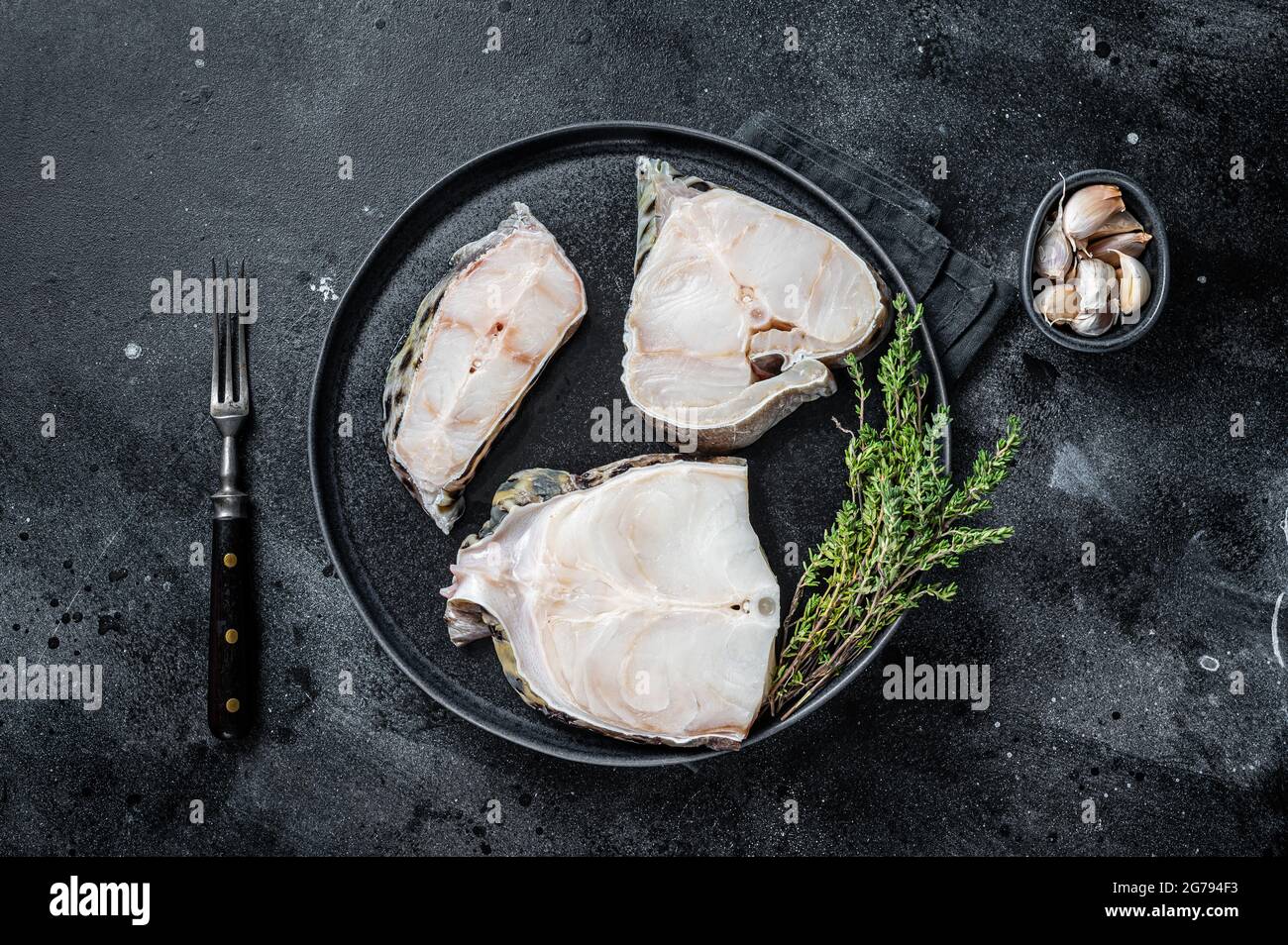 Fresh Raw wolffish o wolf fish Steak on a plate. Black background. Top ...