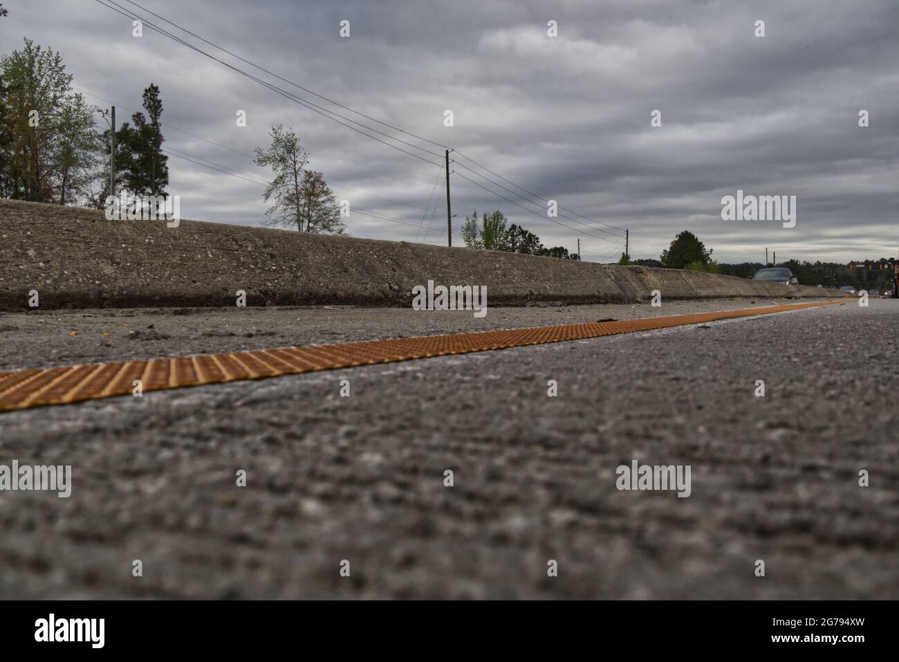 Ground view of a road center divider and oncoming traffic cloudy sky ...