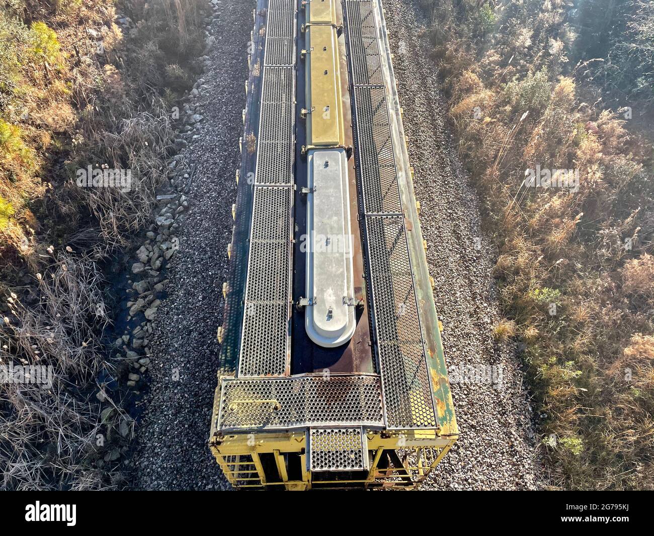 View of the top of a yellow metal mesh top train as it passes under a ...