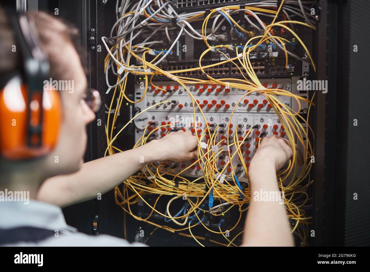 Close up of young network engineer connecting cables in server room ...