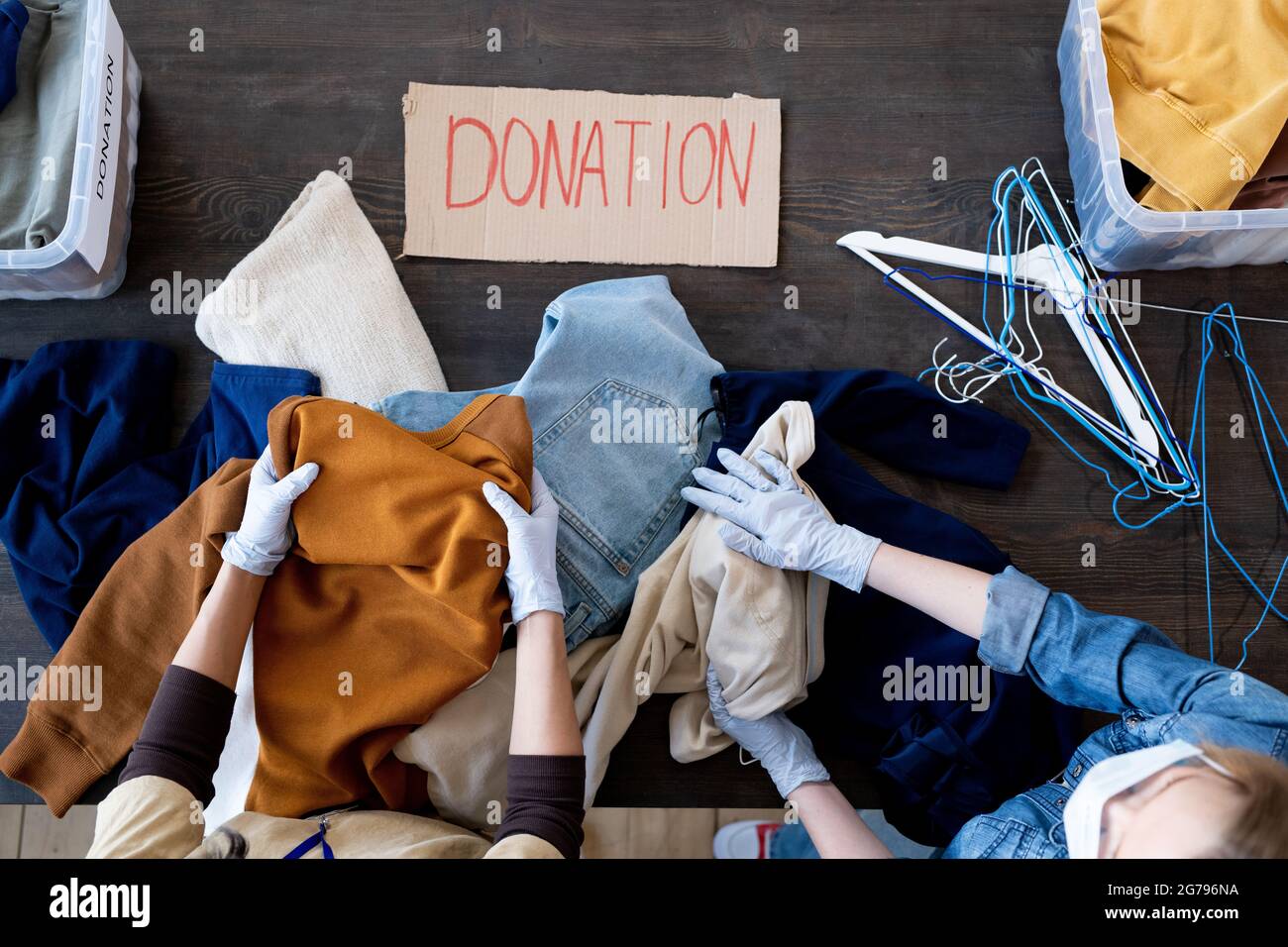 View of gloved females sorting donation clothes by table Stock Photo ...