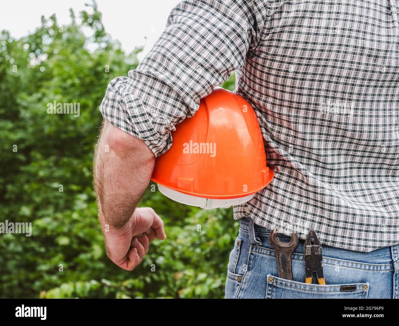 Attractive man in work clothes, holding tools in his hands against the ...