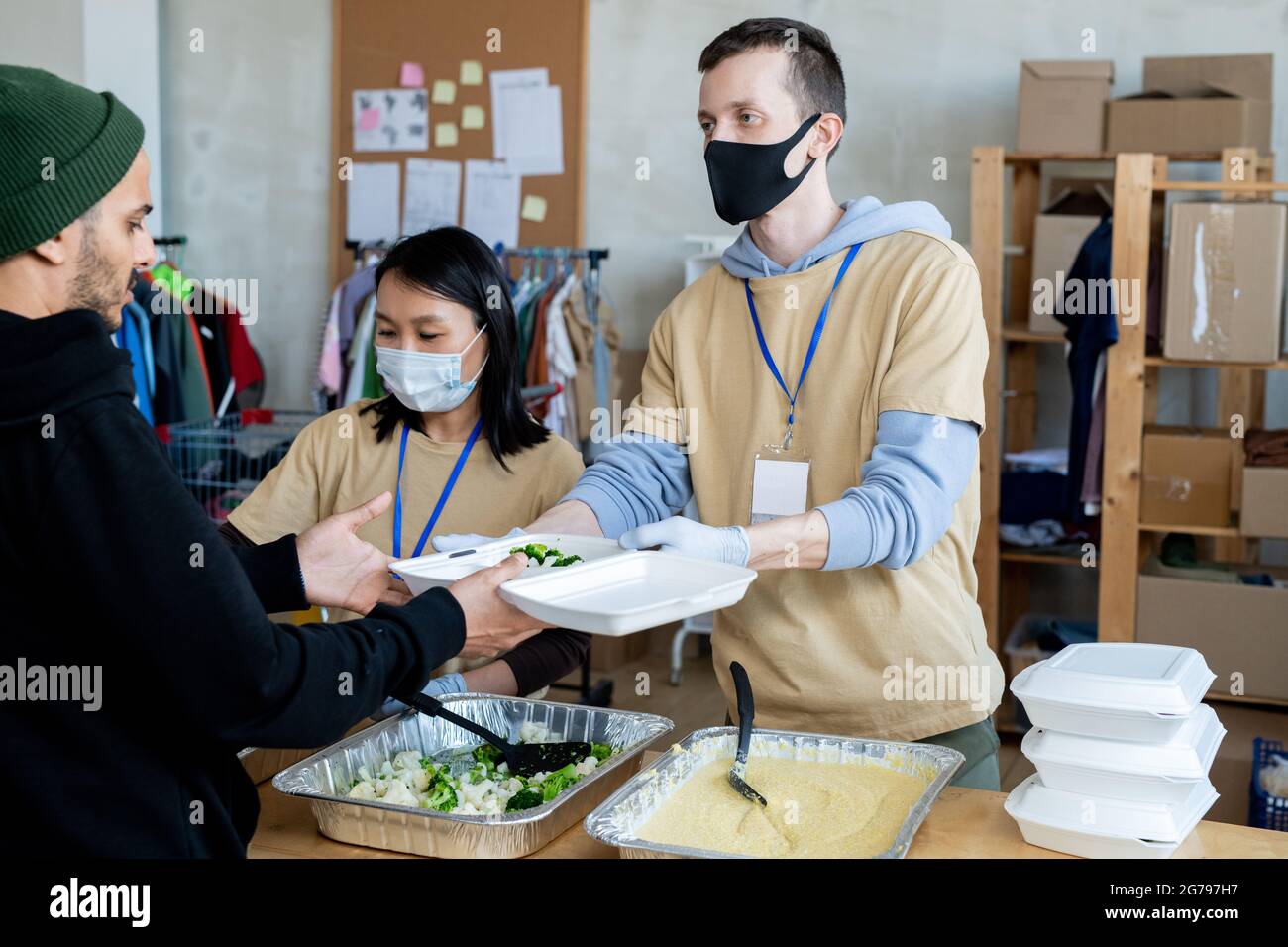 Man in masks and gloves giving free food to hungry guy in volunteering ...