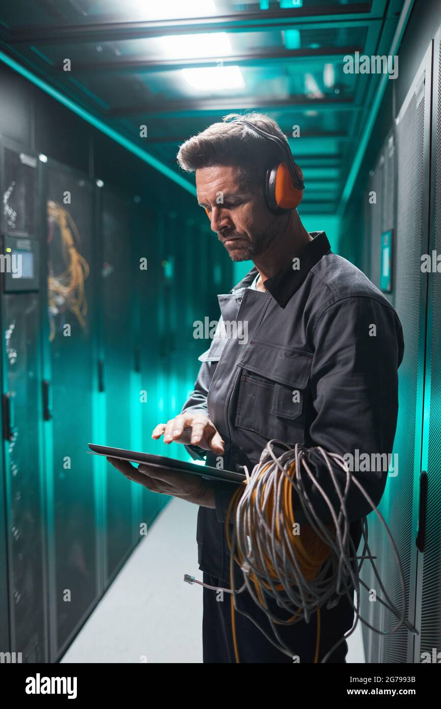 Vertical side view portrait of mature network engineer using digital ...