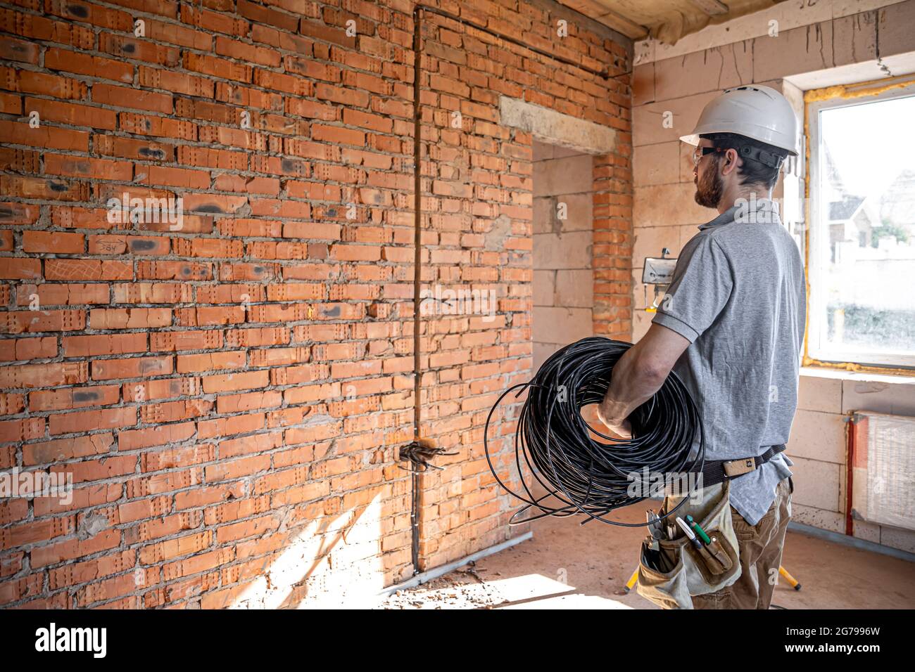 An electrician examines a construction site while holding an electrical ...