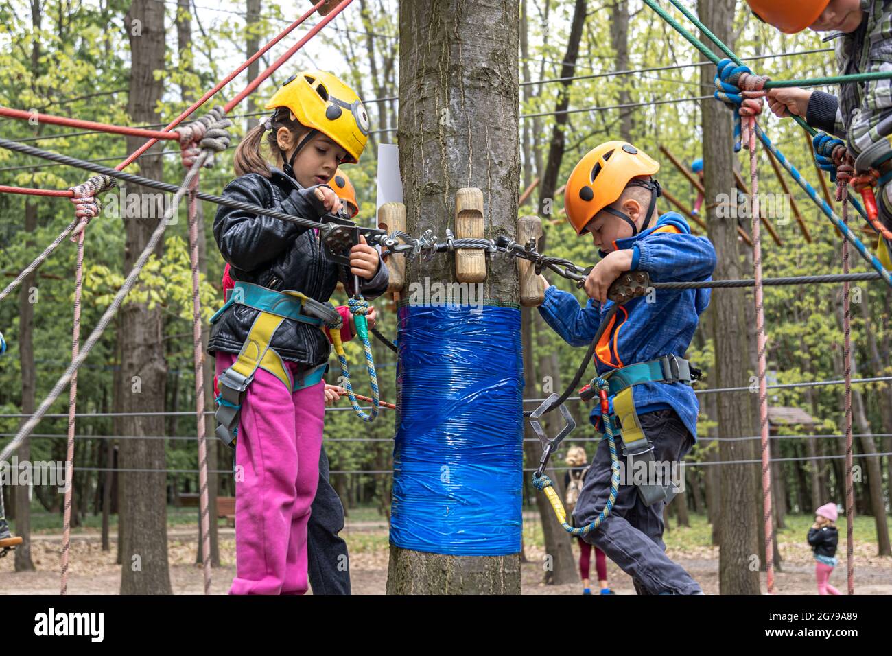 Adventure climbing high wire park - children on course in helmet and ...