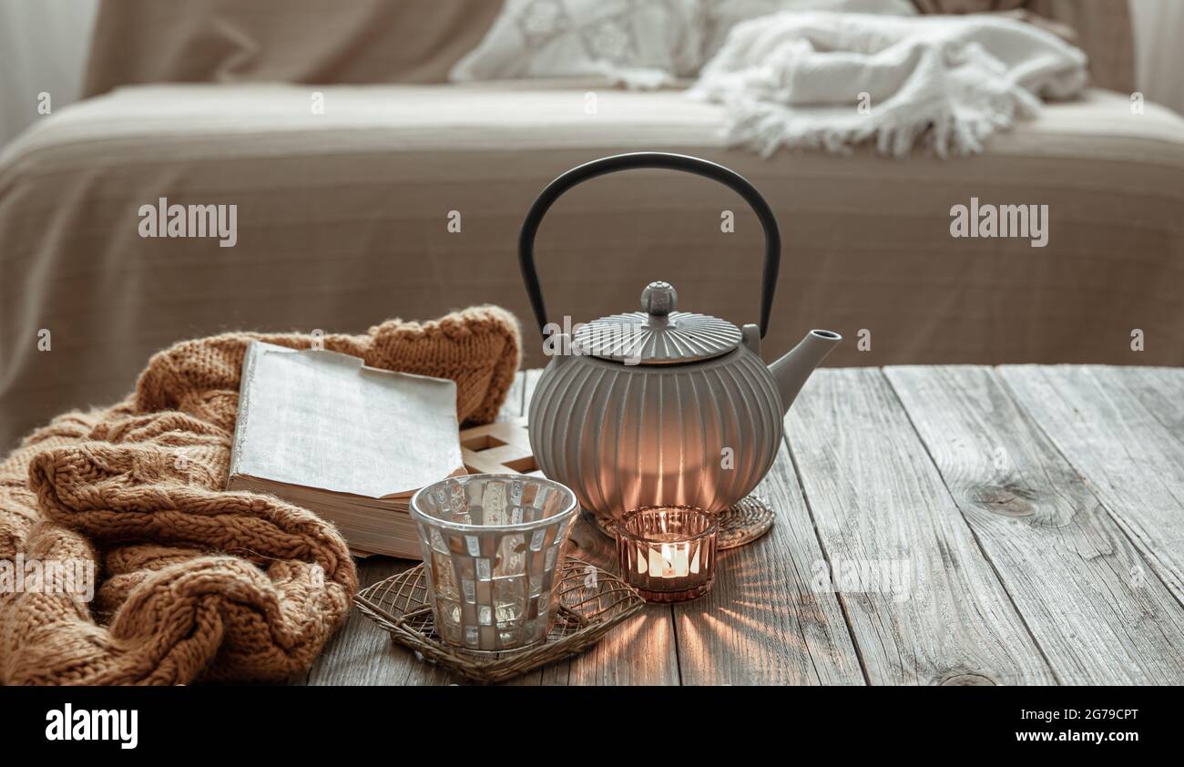 Teapot with tea, knitted item, and candles on the table in the interior ...