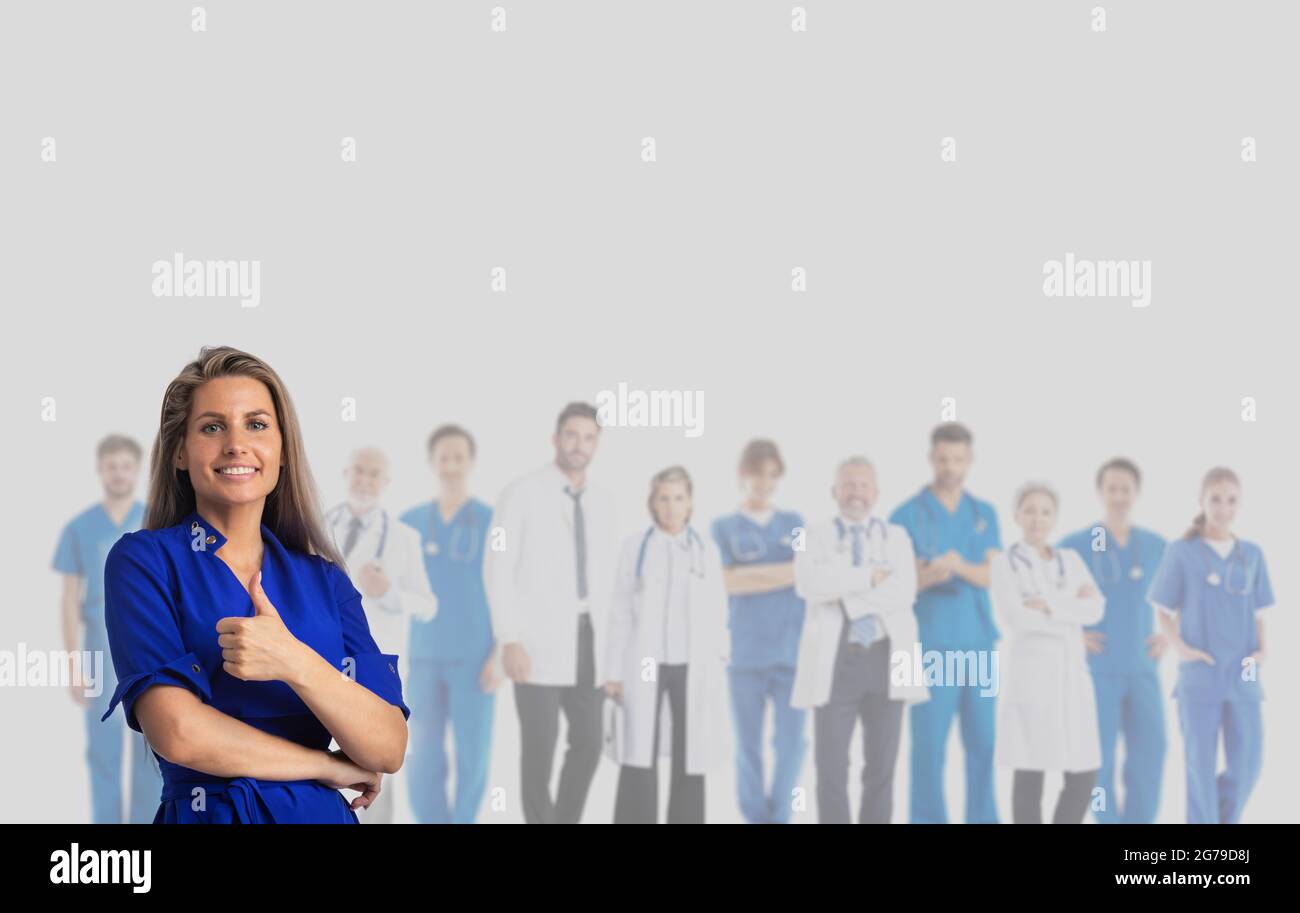 Happy female patient with thumb up and team of doctors on gray ...