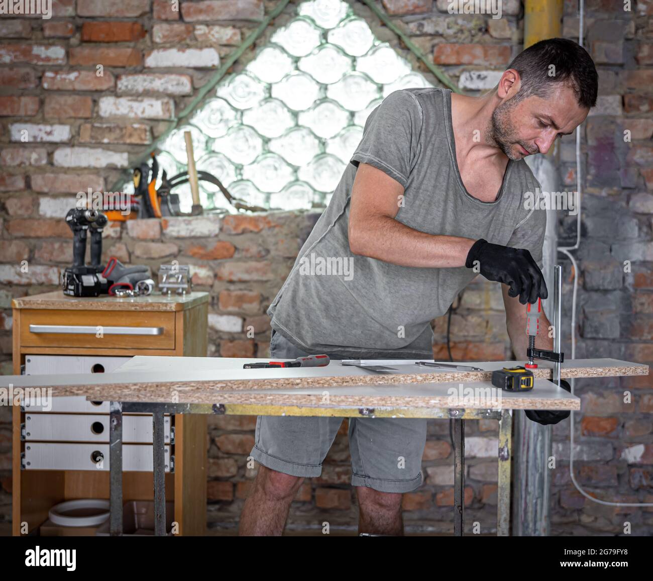 Carpenter doing wood work using clamping hand tool in his workshop ...