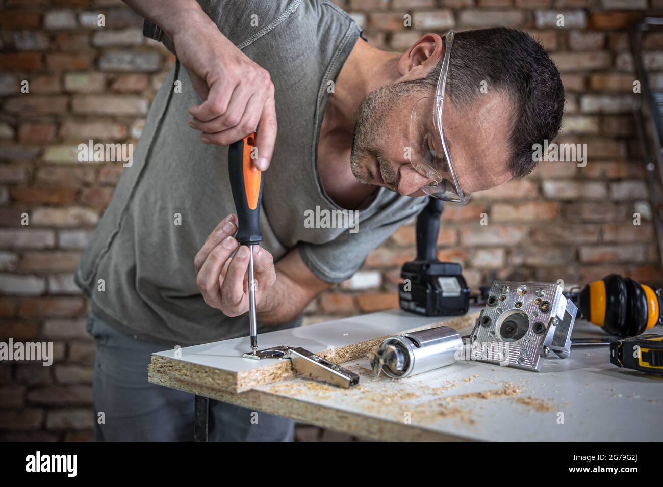 Screwing a self-tapping screw into a metal fastening hole on a wood ...