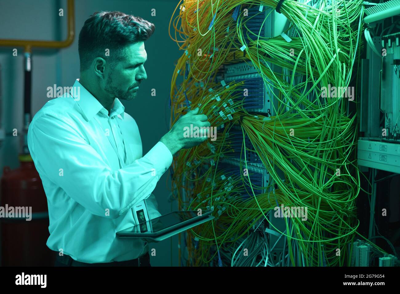 Side view portrait of handsome data engineer inspecting cables in ...