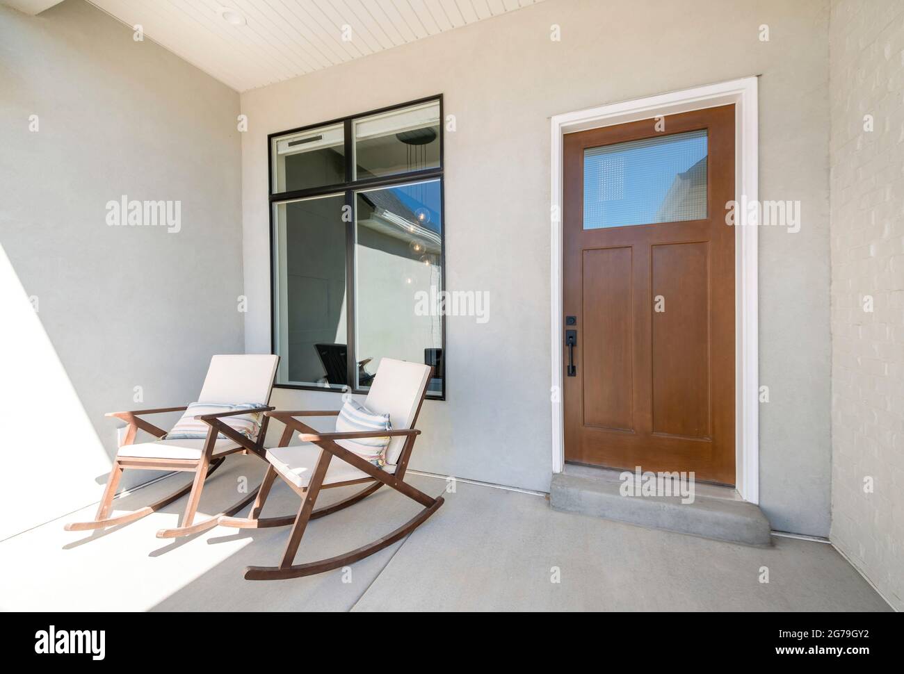 Front porch with two rocking chairs and wooden door with glass panel ...