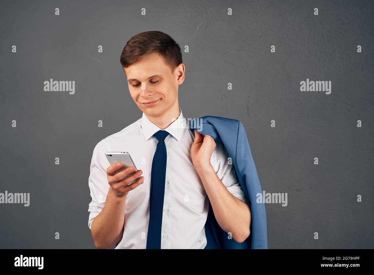 a man in a shirt with a tie with a phone in his hands office work dark ...