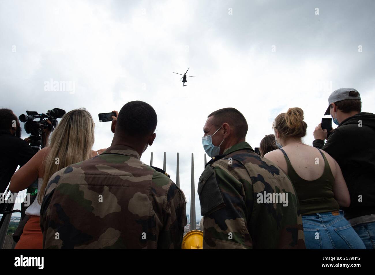 People look at French military Helicopters fly over Paris, during a ...