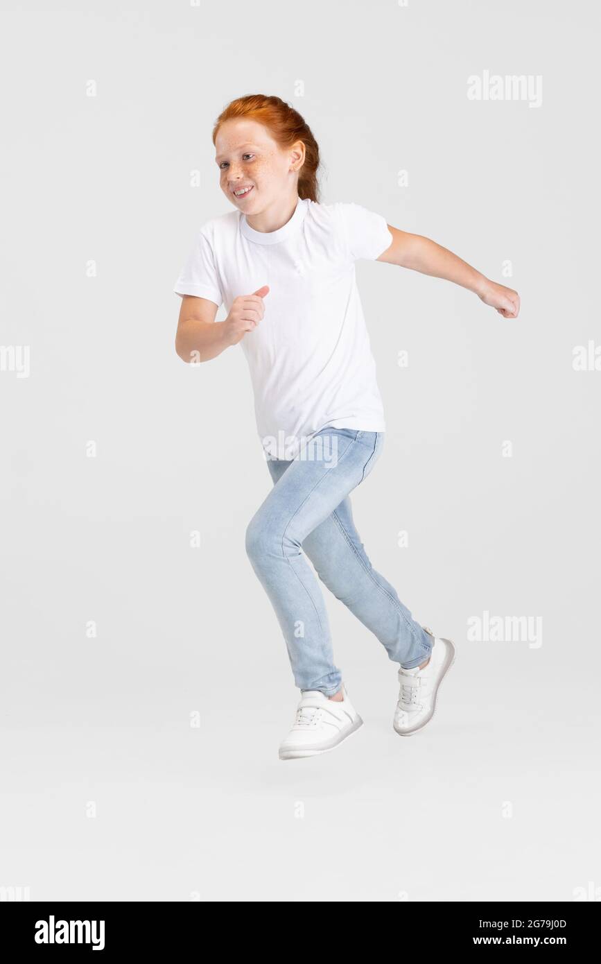 Beautiful cute little red-headed girl in casual outfit running. playing ...