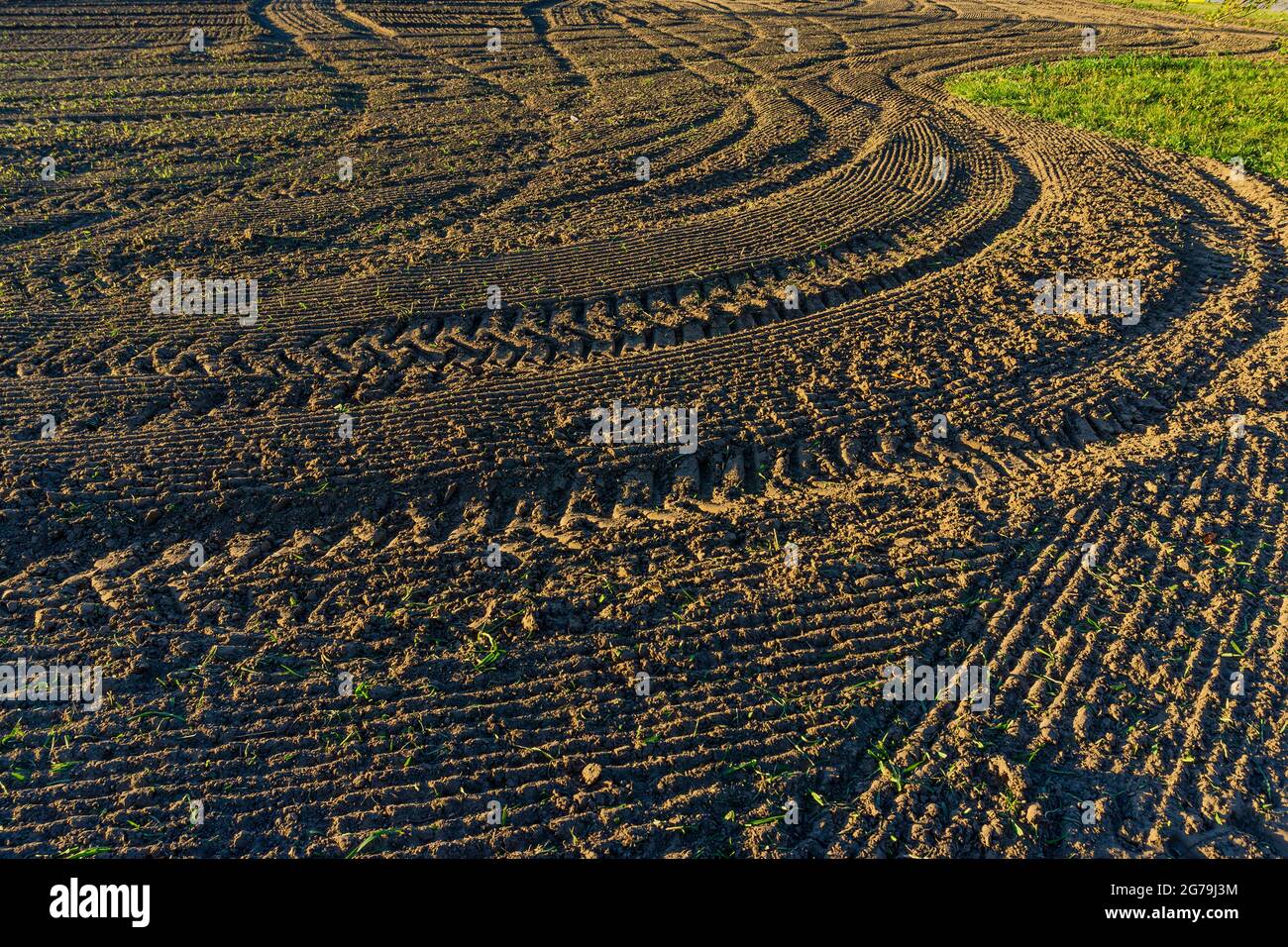 View of a plowed field with traces and furrows of a tractor meandering ...