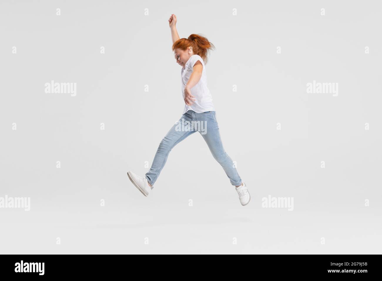 Beautiful cute little red-headed girl in casual outfit running. playing ...