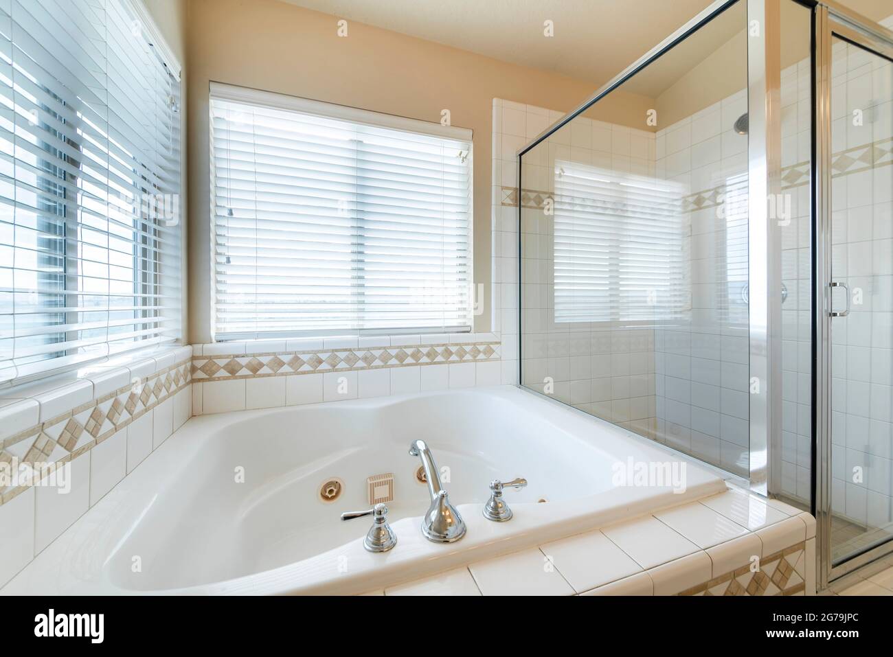 Drop in bathtub beside the glass shower stall against the windows Stock ...
