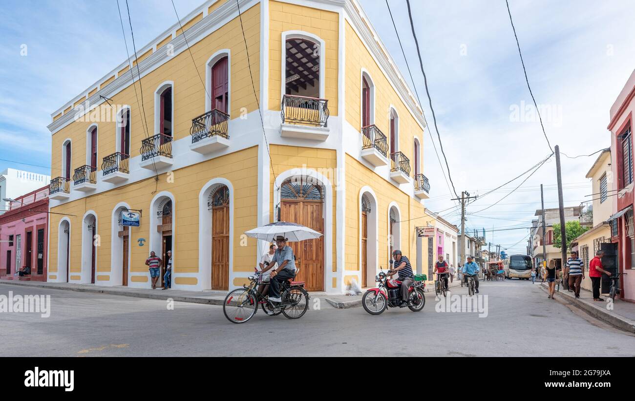 A bicitaxi or pedicab driving by building architecture facade, Holguin ...