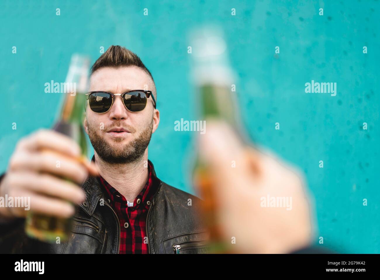 Bearded cool man toasting beer with best friend outdoor against a blue ...