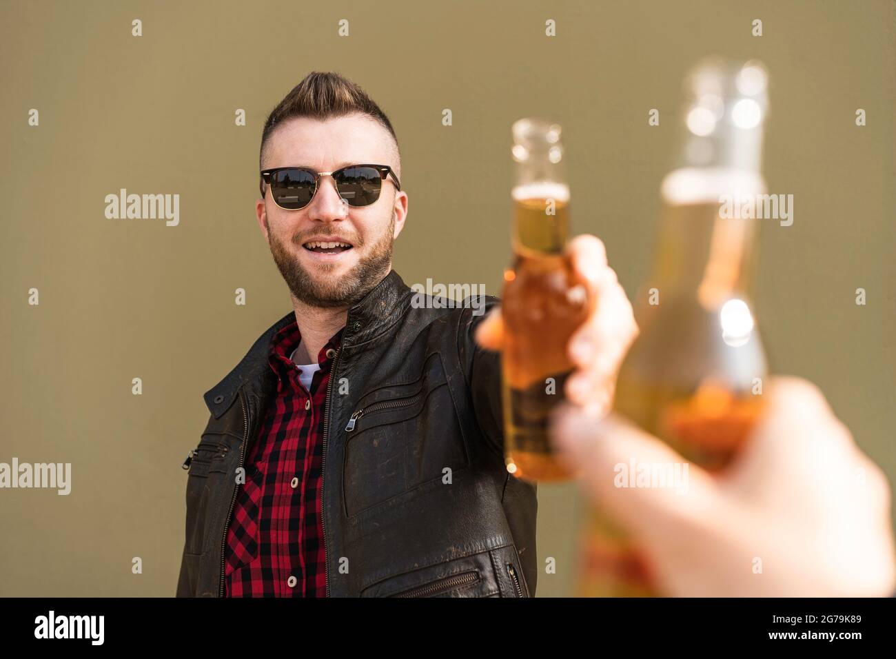 Unshaven cool man toasting beer with best friend outdoor against a ...