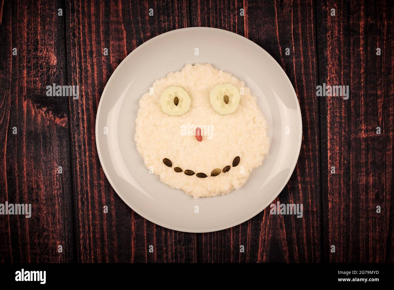 Food smile face. Funny eating concept with rice, nuts and cucumbers ...