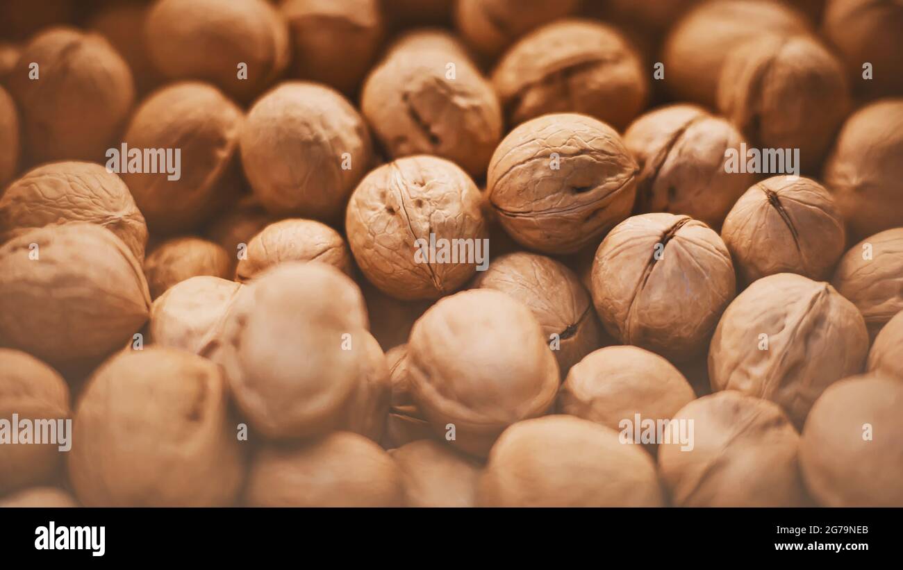 A lot of walnuts in brown shells are on sale in a grocery store. The ...