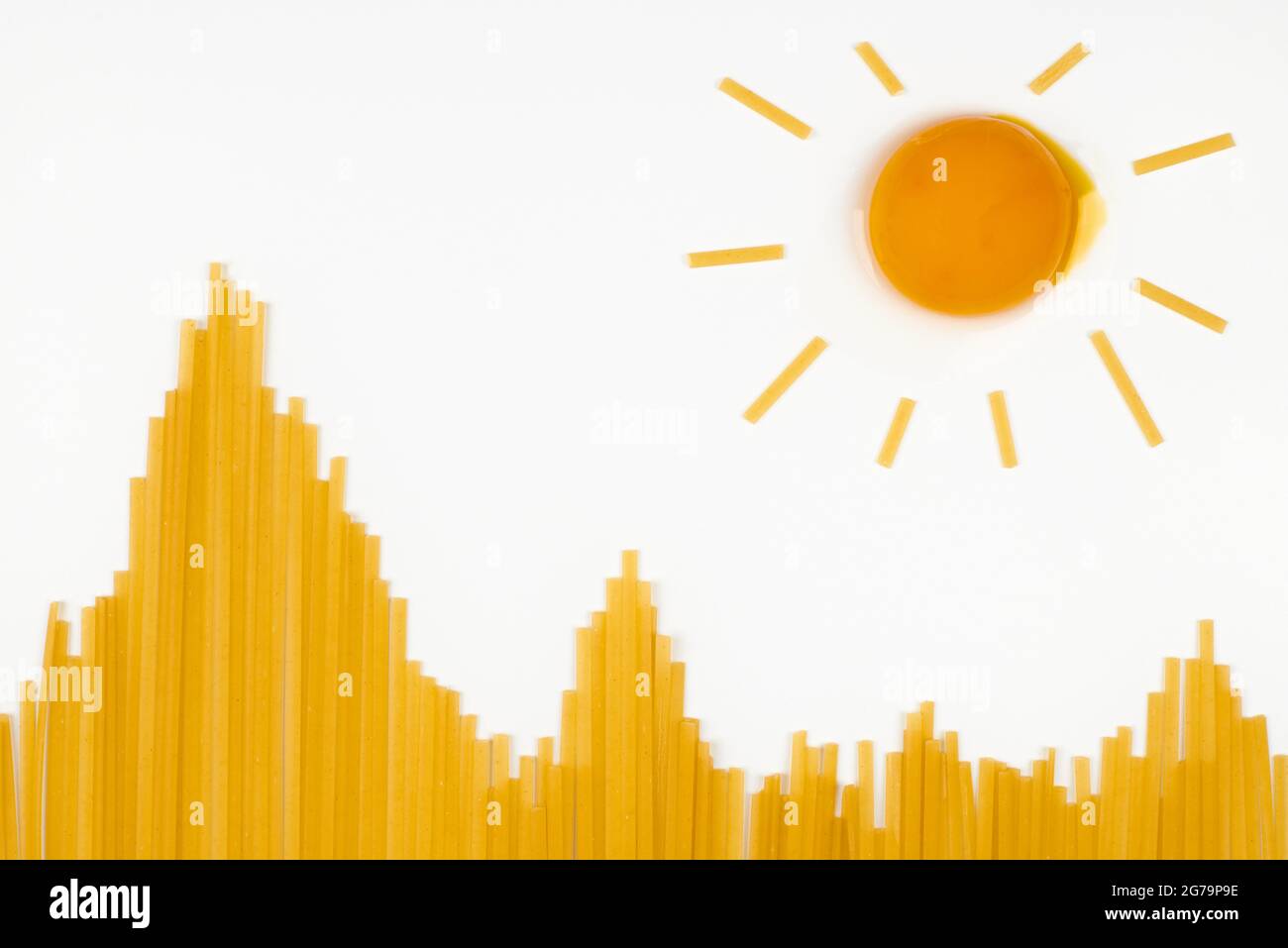 Sun in mountains. Uncooked spaghetti in shape of hills and egg as sun ...