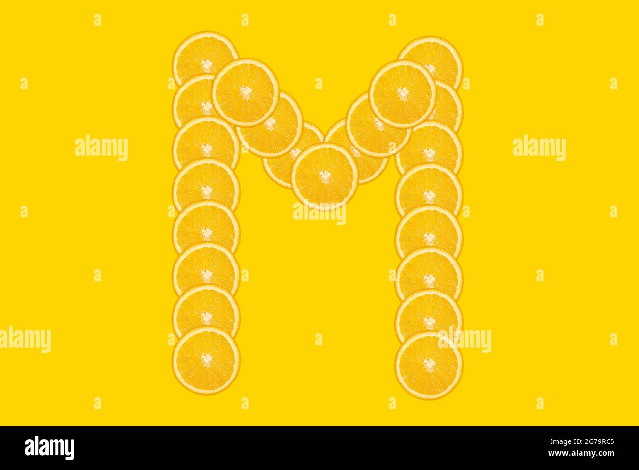 Sliced orange alphabet - letter M. Yellow background. Fresh healthy ...