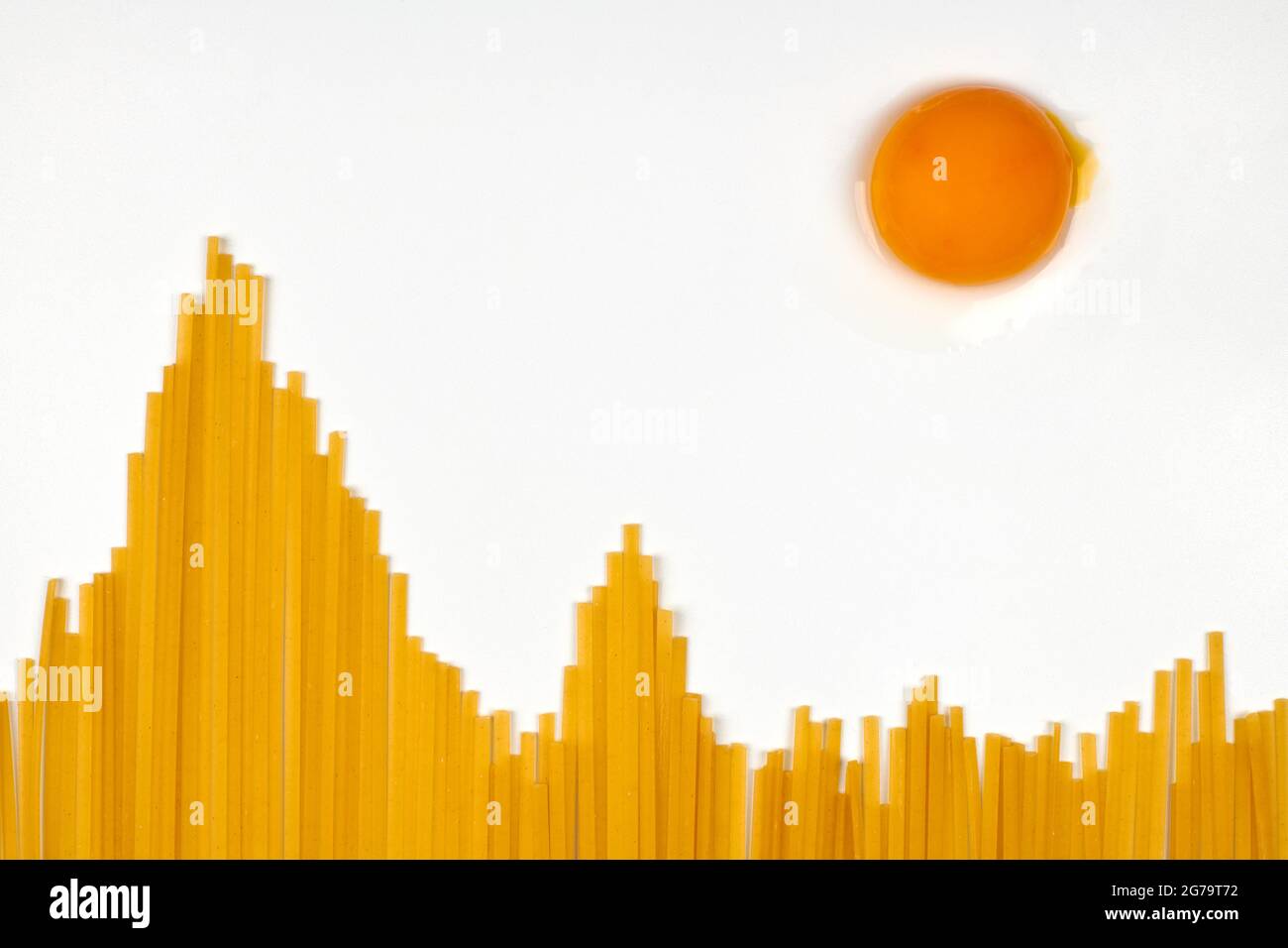 Sun in mountains. Uncooked spaghetti in shape of hills and egg as sun ...
