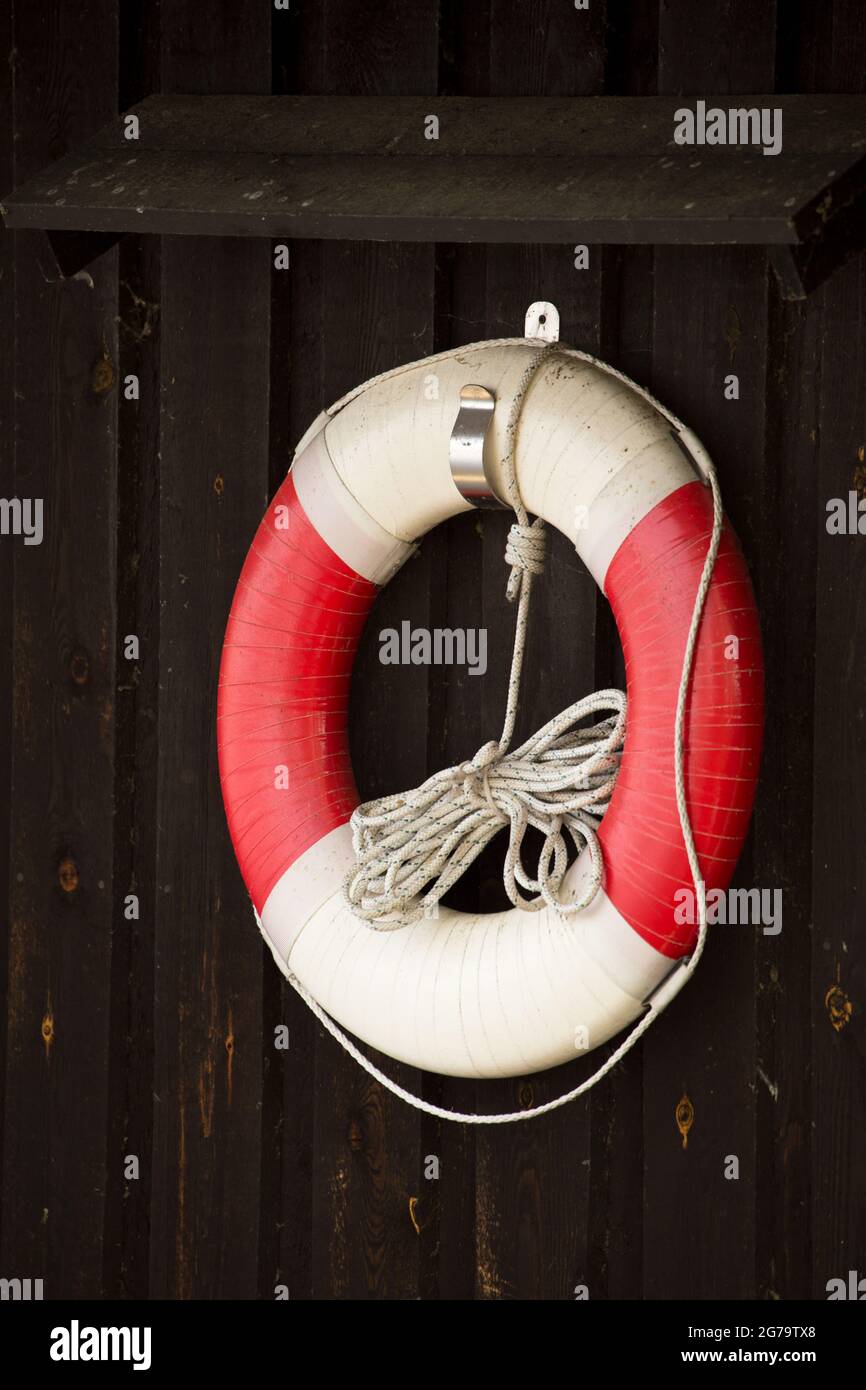 Lifebuoy with floating rope hanging on dark wooden wall Stock Photo - Alamy