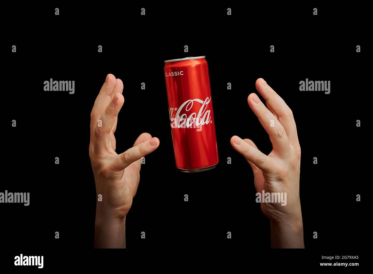 KALININGRAD, RUSSIA - MARCH 13, 2021 - Hands catch Coca Cola can, black ...