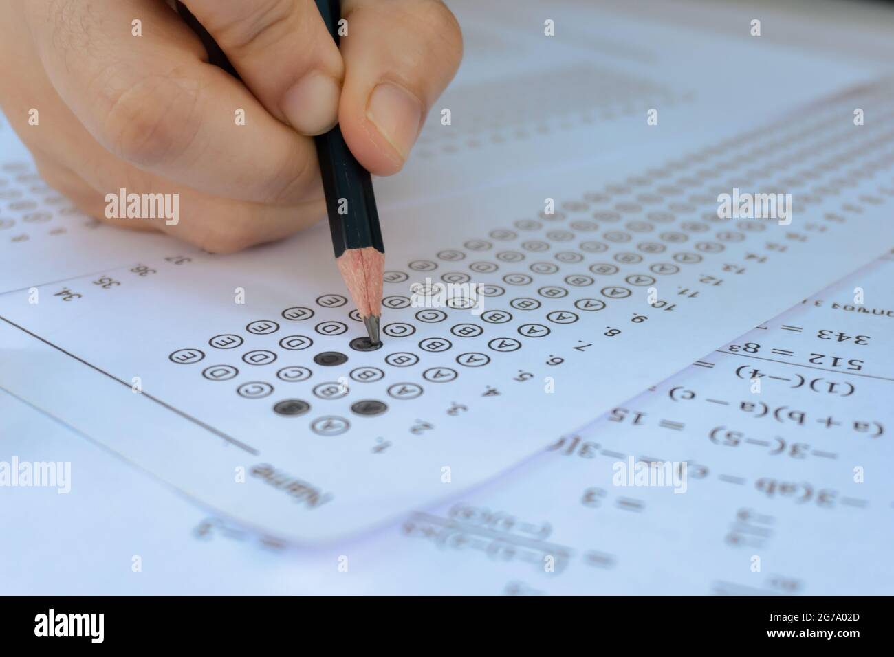 Students hand holding pencil writing selected choice on answer sheets ...