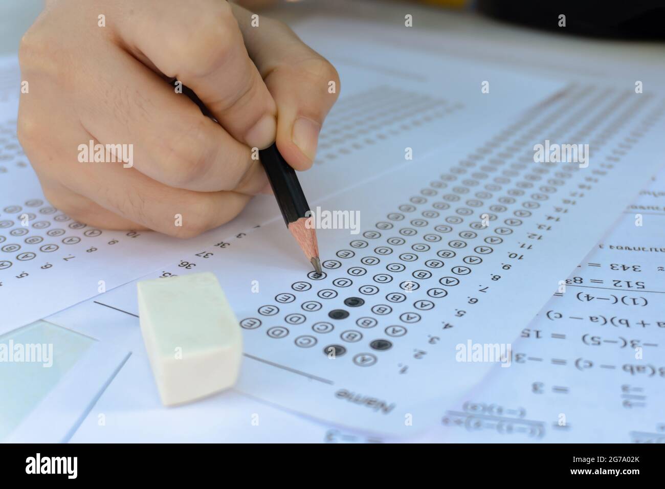 Students hand holding pencil writing selected choice on answer sheets ...