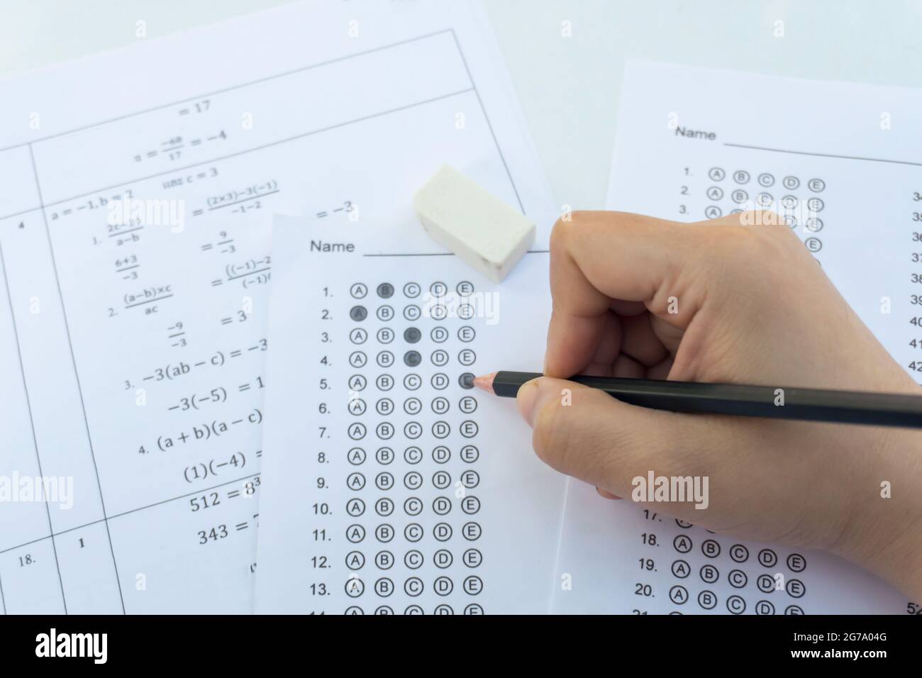 Students hand holding pencil writing selected choice on answer sheets ...