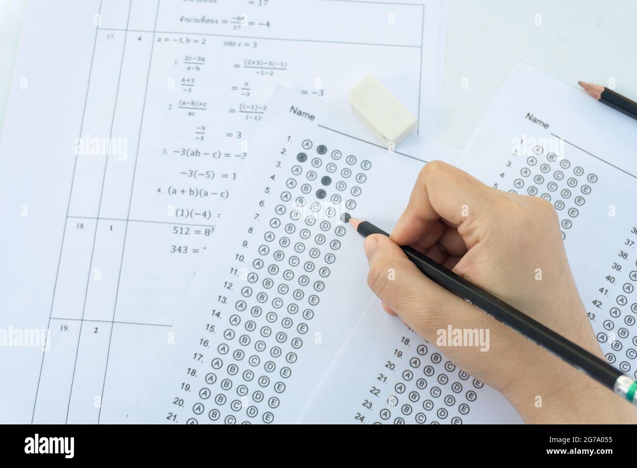 Students hand holding pencil writing selected choice on answer sheets ...
