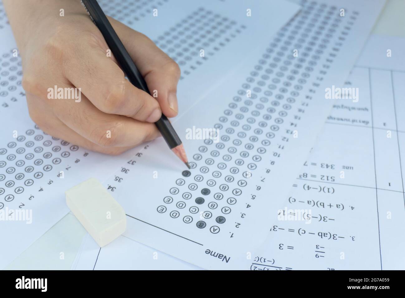 Students hand holding pencil writing selected choice on answer sheets ...