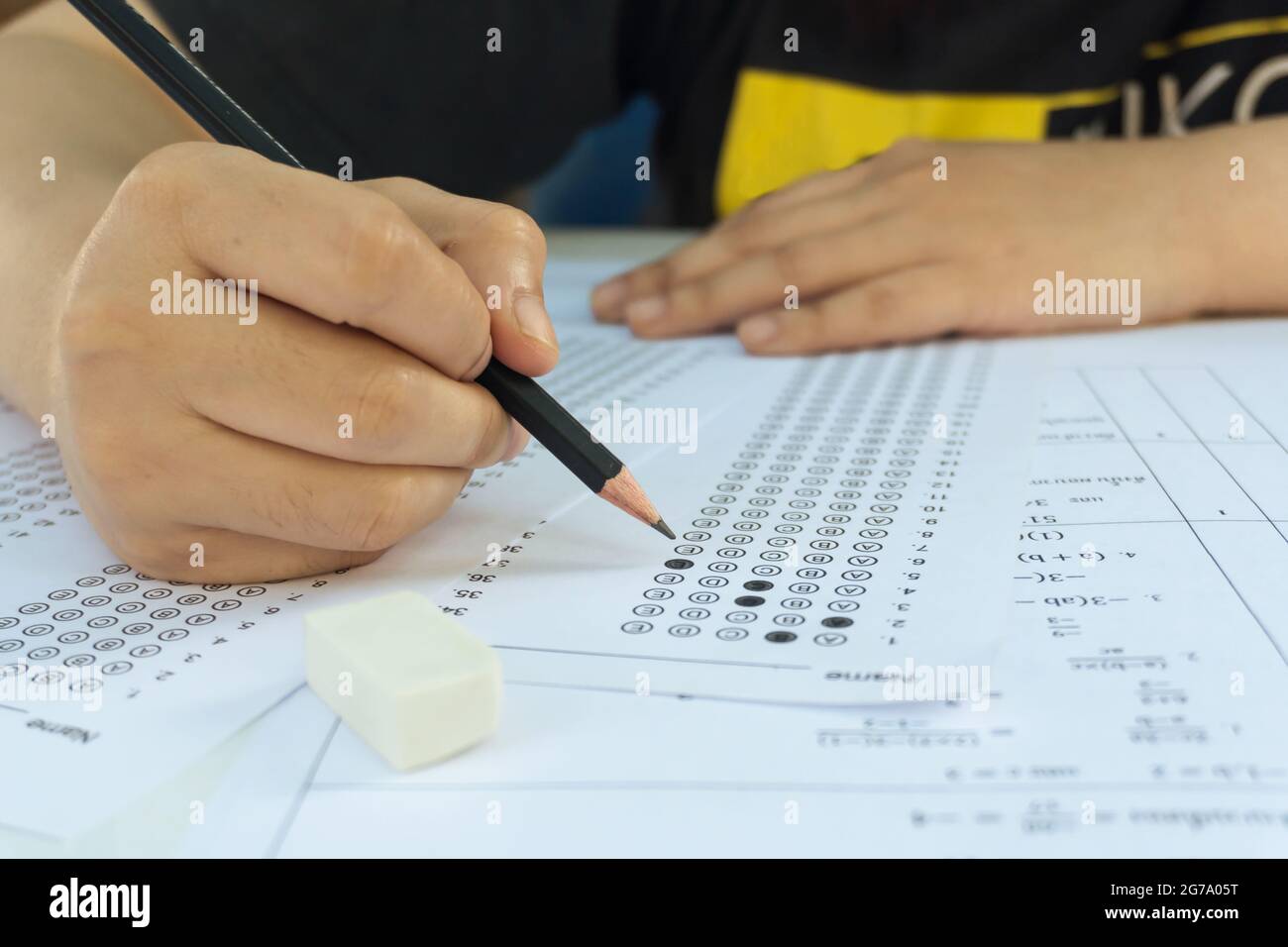 Woman students hand holding pencil writing selected choice on answer ...