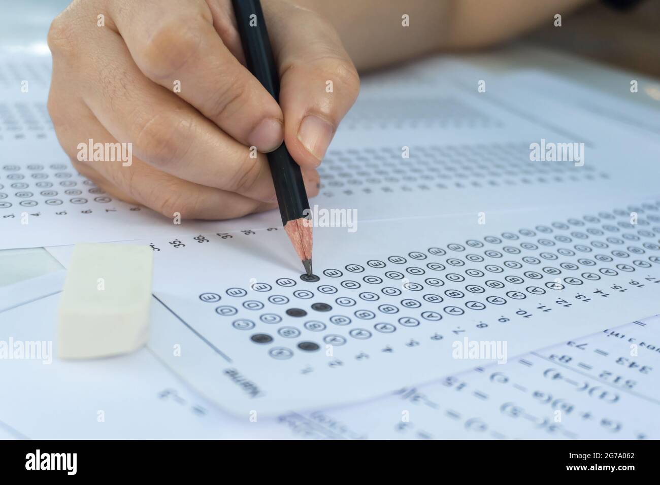 Students hand holding pencil writing selected choice on answer sheets ...