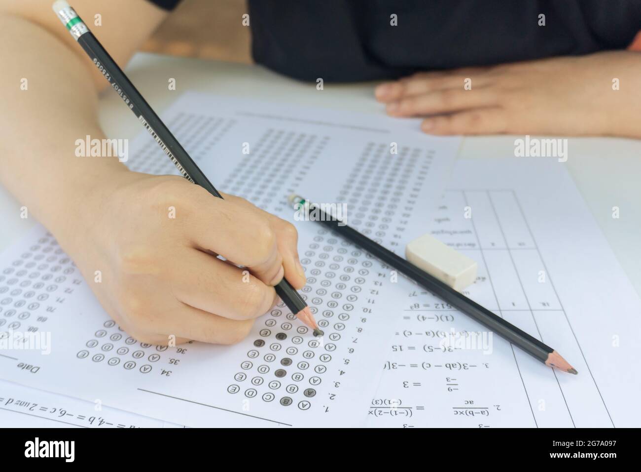 Students hand holding pencil writing selected choice on answer sheets ...
