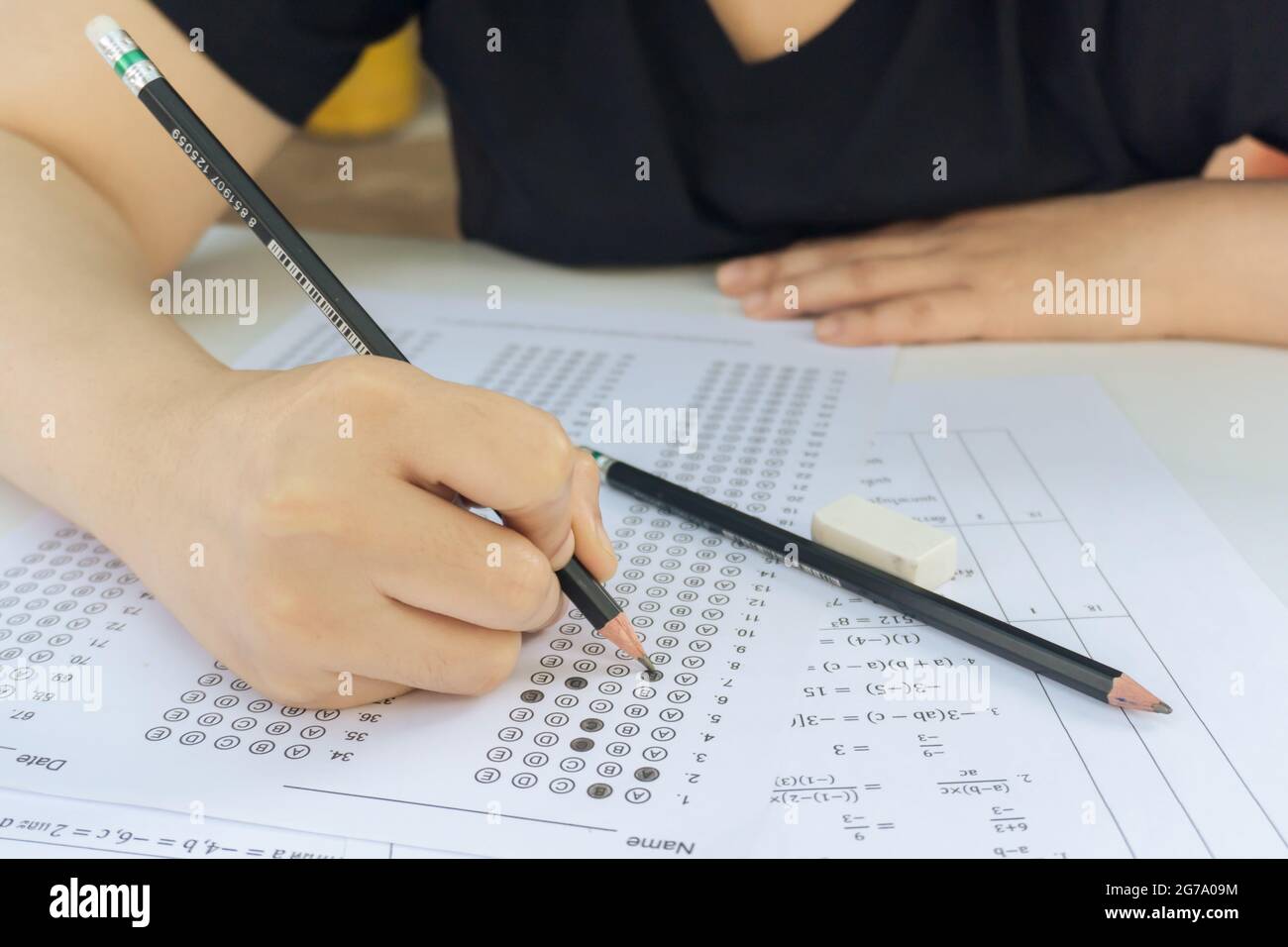 Woman students hand holding pencil writing selected choice on answer ...