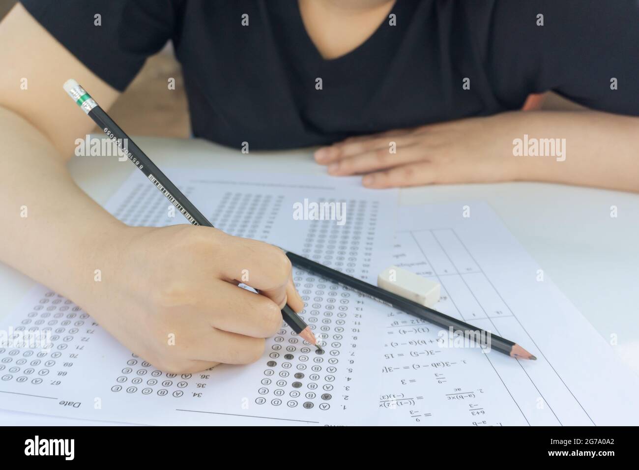 Woman students hand holding pencil writing selected choice on answer ...