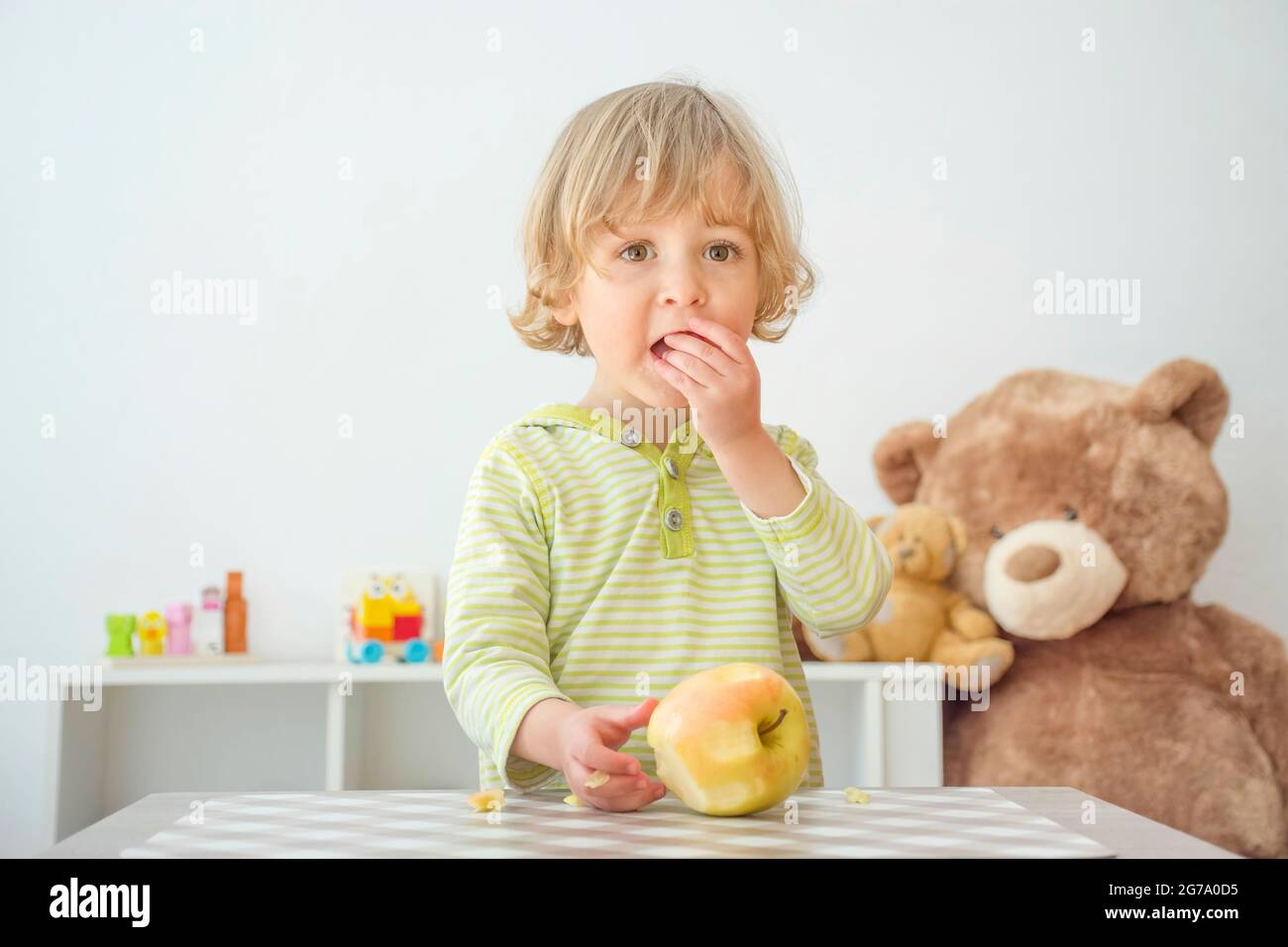 Cute happy child boy having fun eating a big fresh yellow apple fruit ...