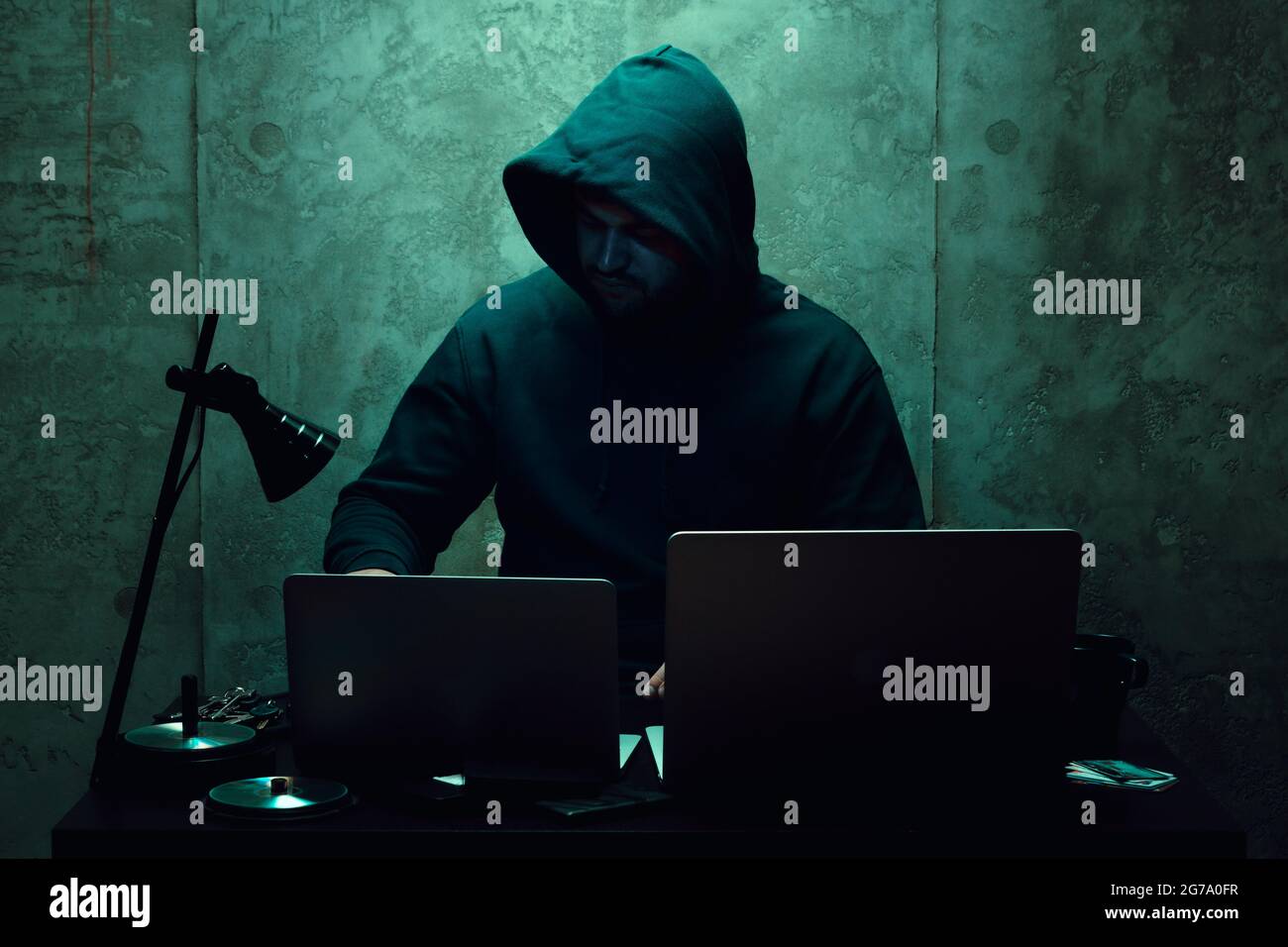 Anonymous hacker wearing face mask working on computer in dark room ...